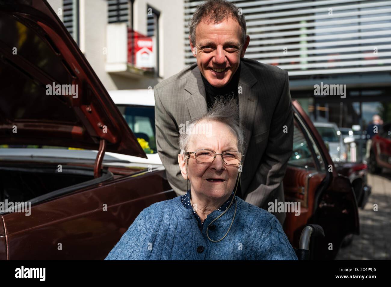 85 yo woman and 57 yo man posing in front of an old timer car during a ...