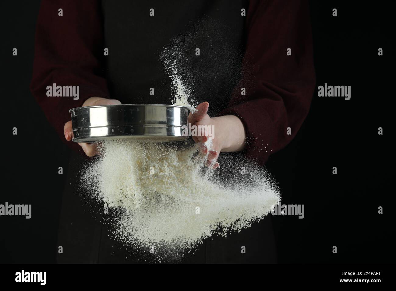 Woman sieving flour against black background, closeup Stock Photo - Alamy