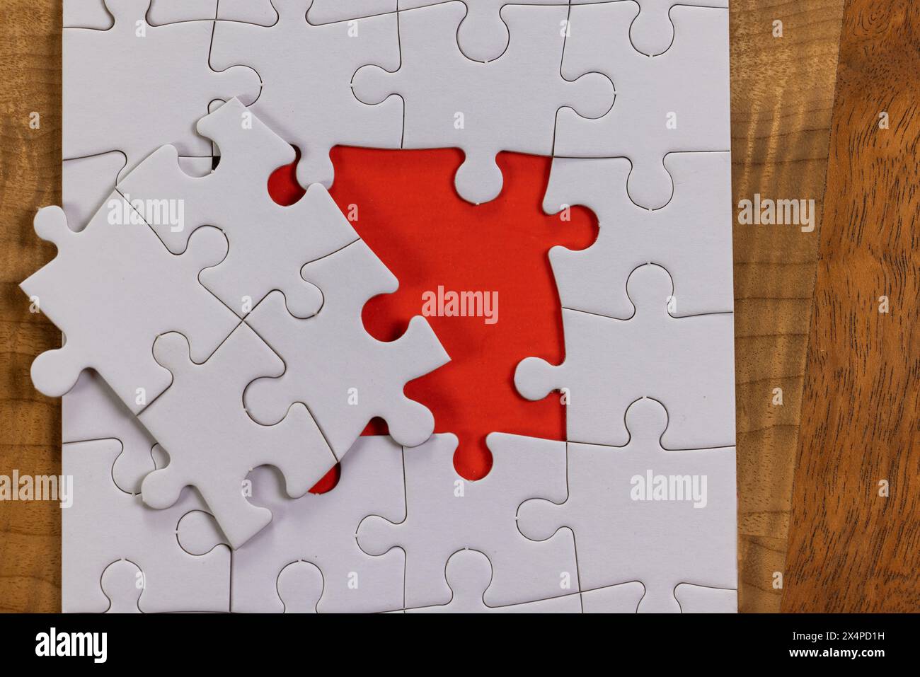 Blank puzzle with one missing piece next to the whole with a red placer where the last piece ...