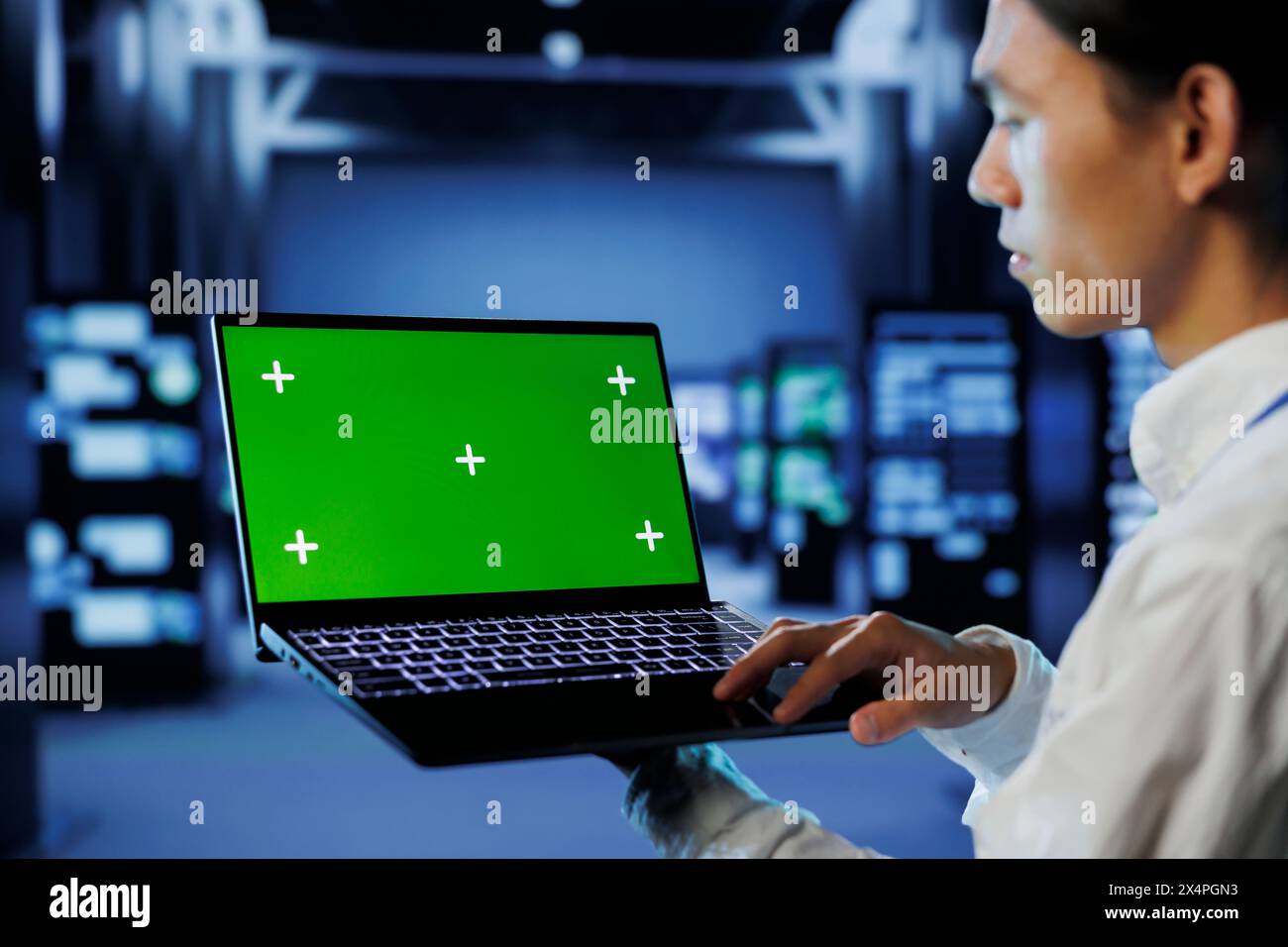 IT consultant with green screen laptop between server hub clusters providing processing ...