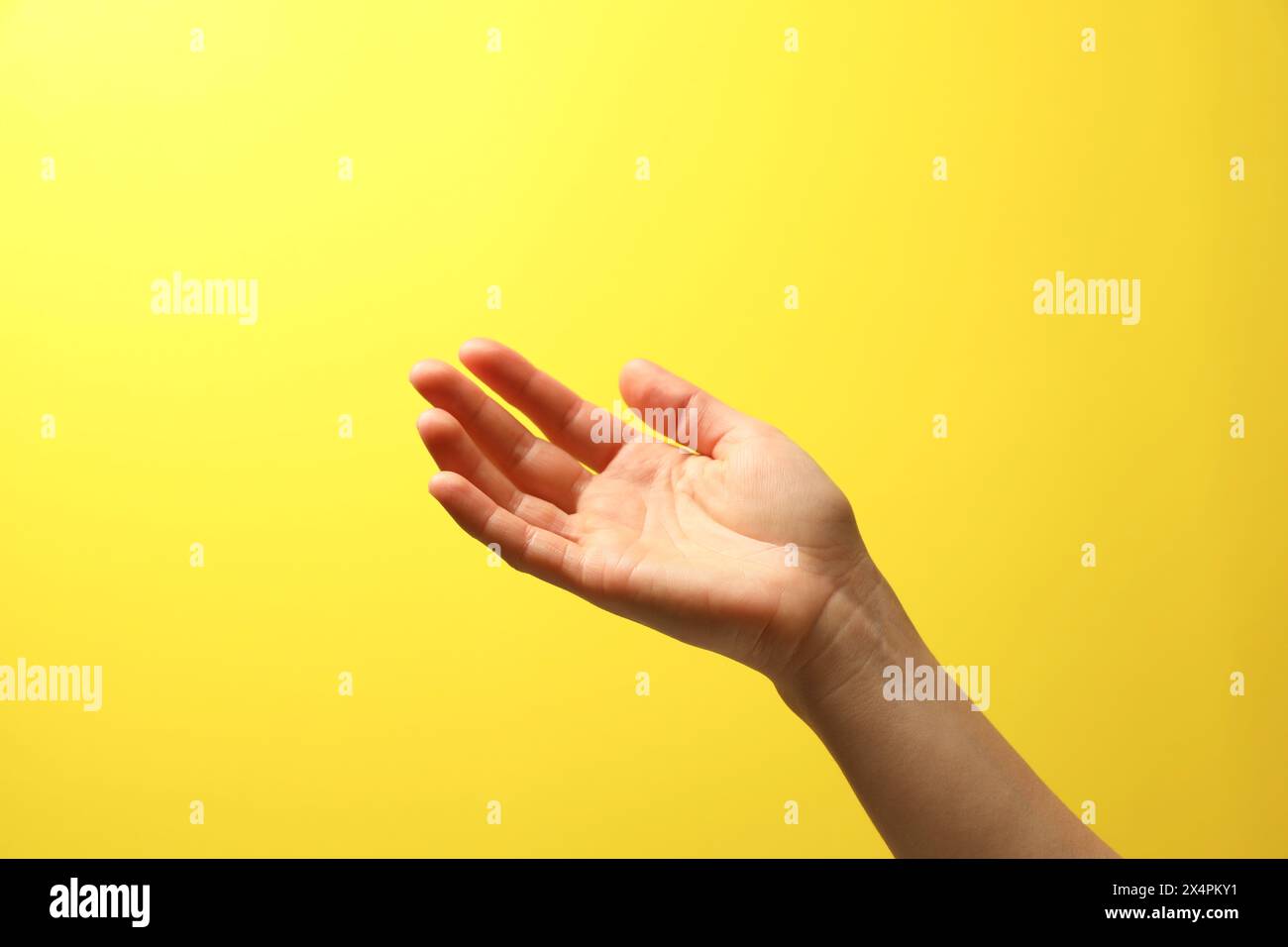 Woman holding something in hand on yellow background, closeup Stock ...