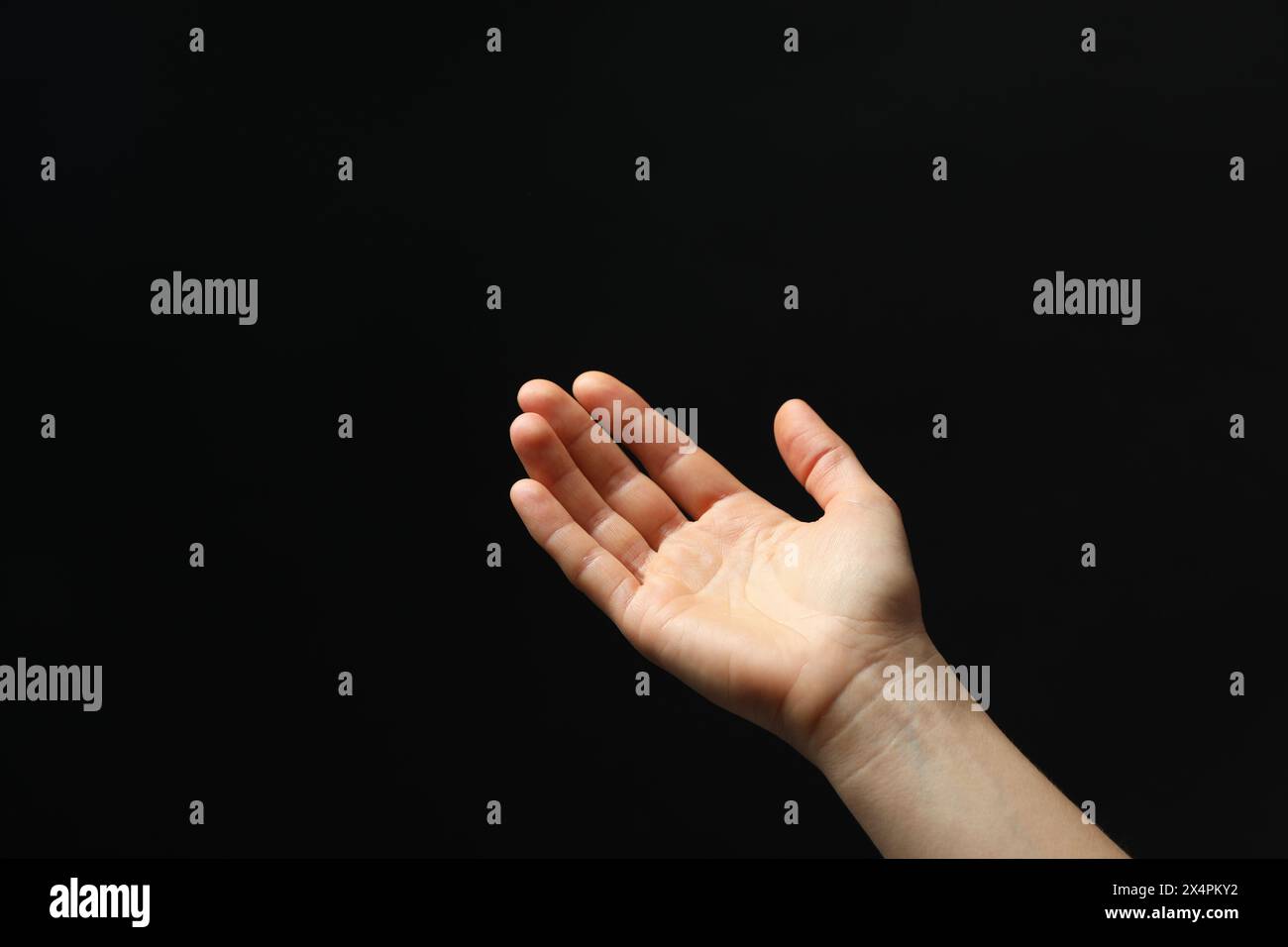 Woman holding something in hand on black background, closeup. Space for ...