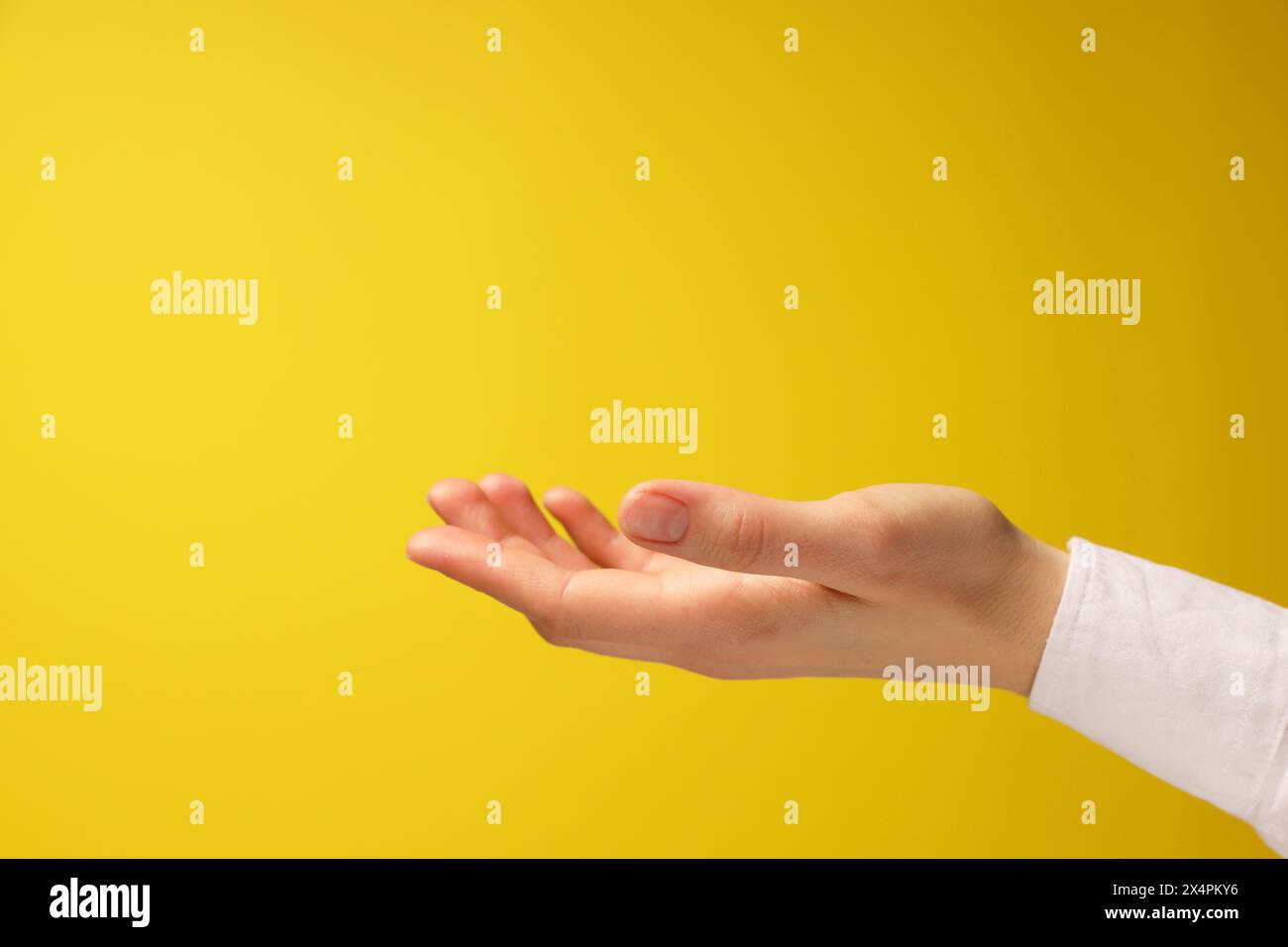 Woman holding something in hand on yellow background, closeup. Space ...