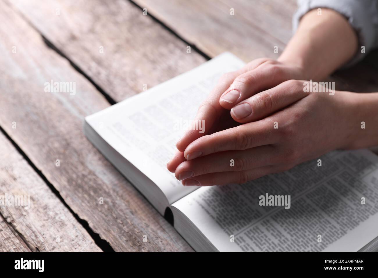 Religion. Christian woman praying over Bible at wooden table, closeup ...