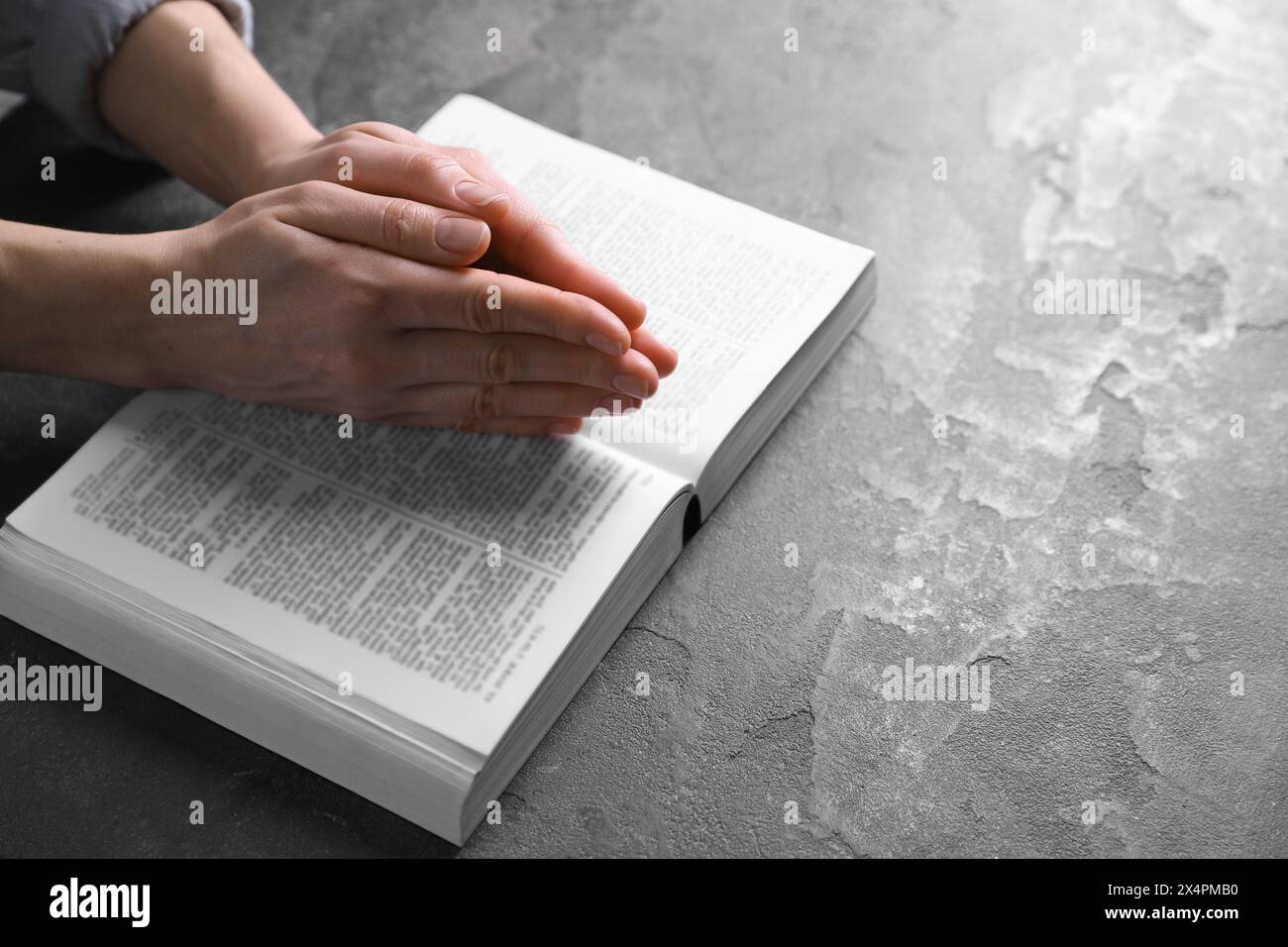 Religion. Christian woman praying over Bible at gray table, closeup ...