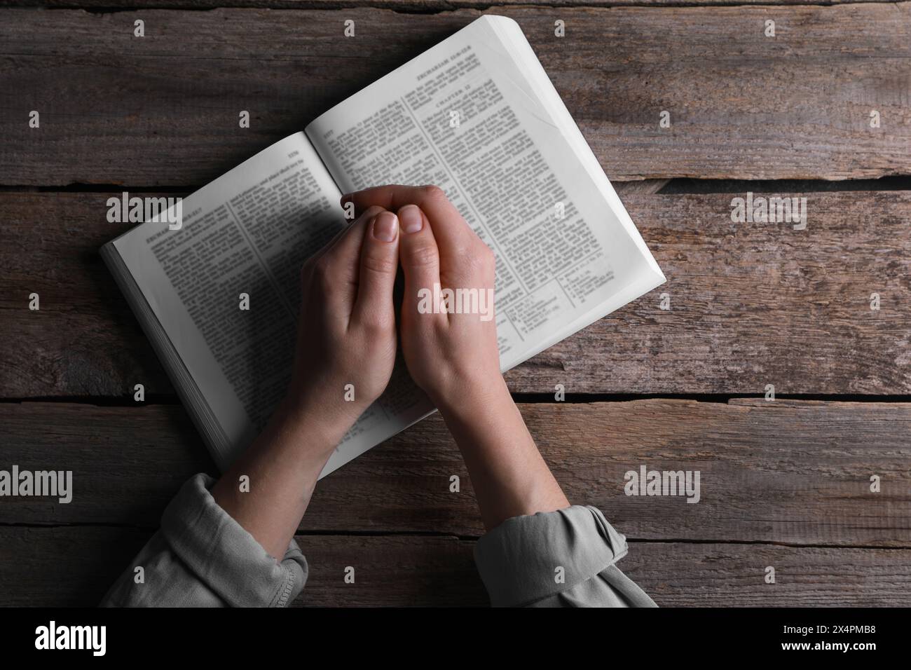 Religion. Christian woman praying over Bible at wooden table, top view ...