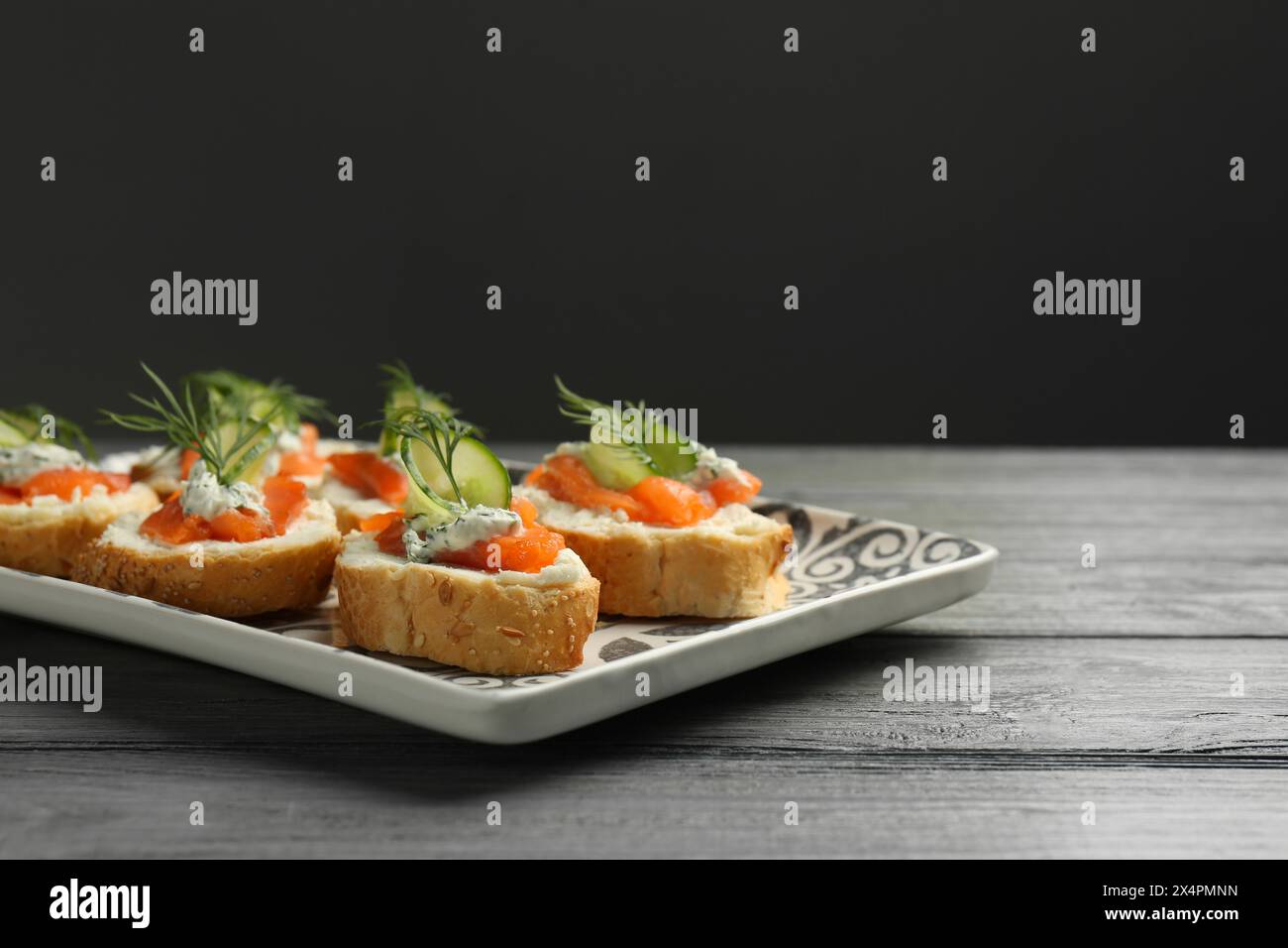 Tasty canapes with salmon, cucumber, cream cheese and dill on wooden ...