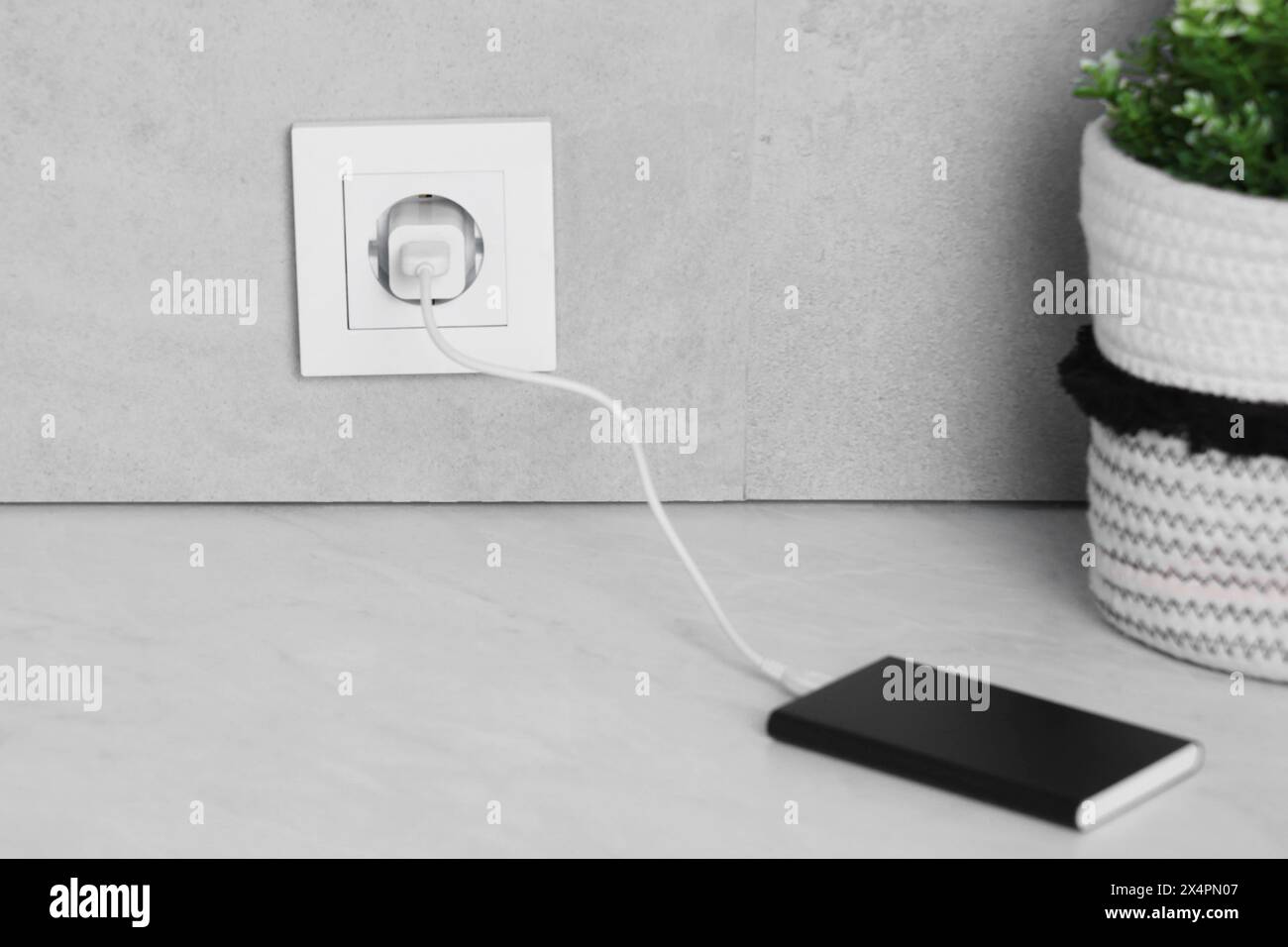 Power bank plugged into electric socket on white table Stock Photo - Alamy