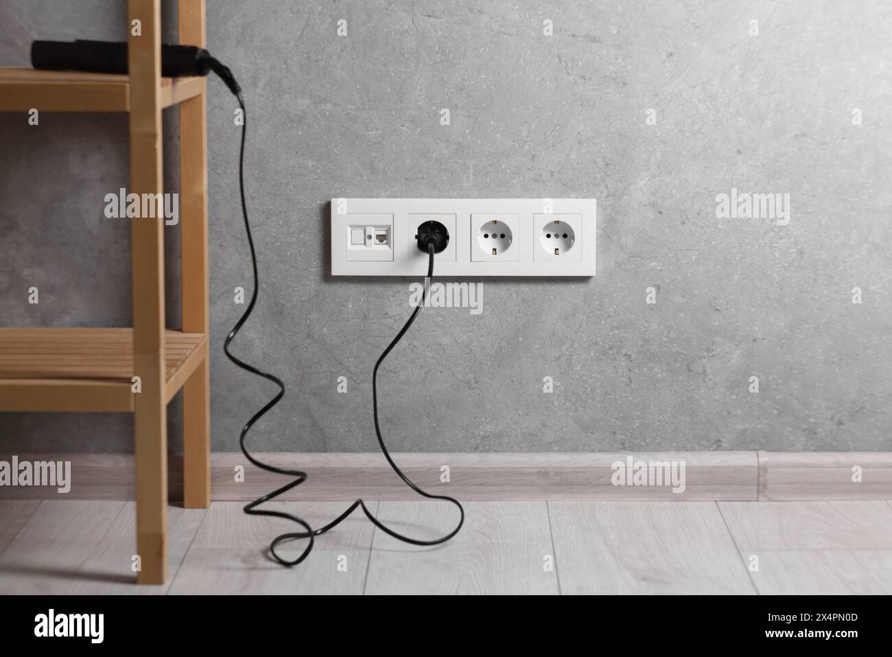 Power sockets and electric plug on grey wall Stock Photo - Alamy