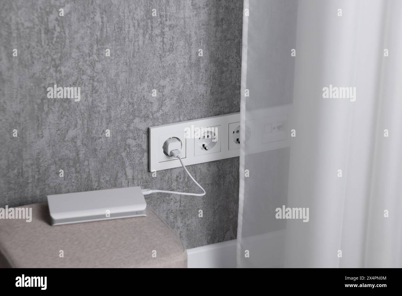 Power bank plugged into electric socket on grey wall Stock Photo - Alamy