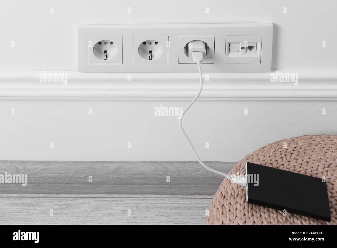 Power bank plugged into electric socket on white wall Stock Photo - Alamy