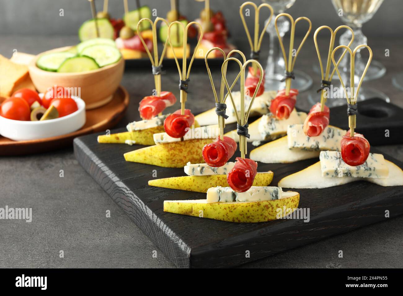 Tasty canapes with pears, blue cheese and prosciutto on grey table ...