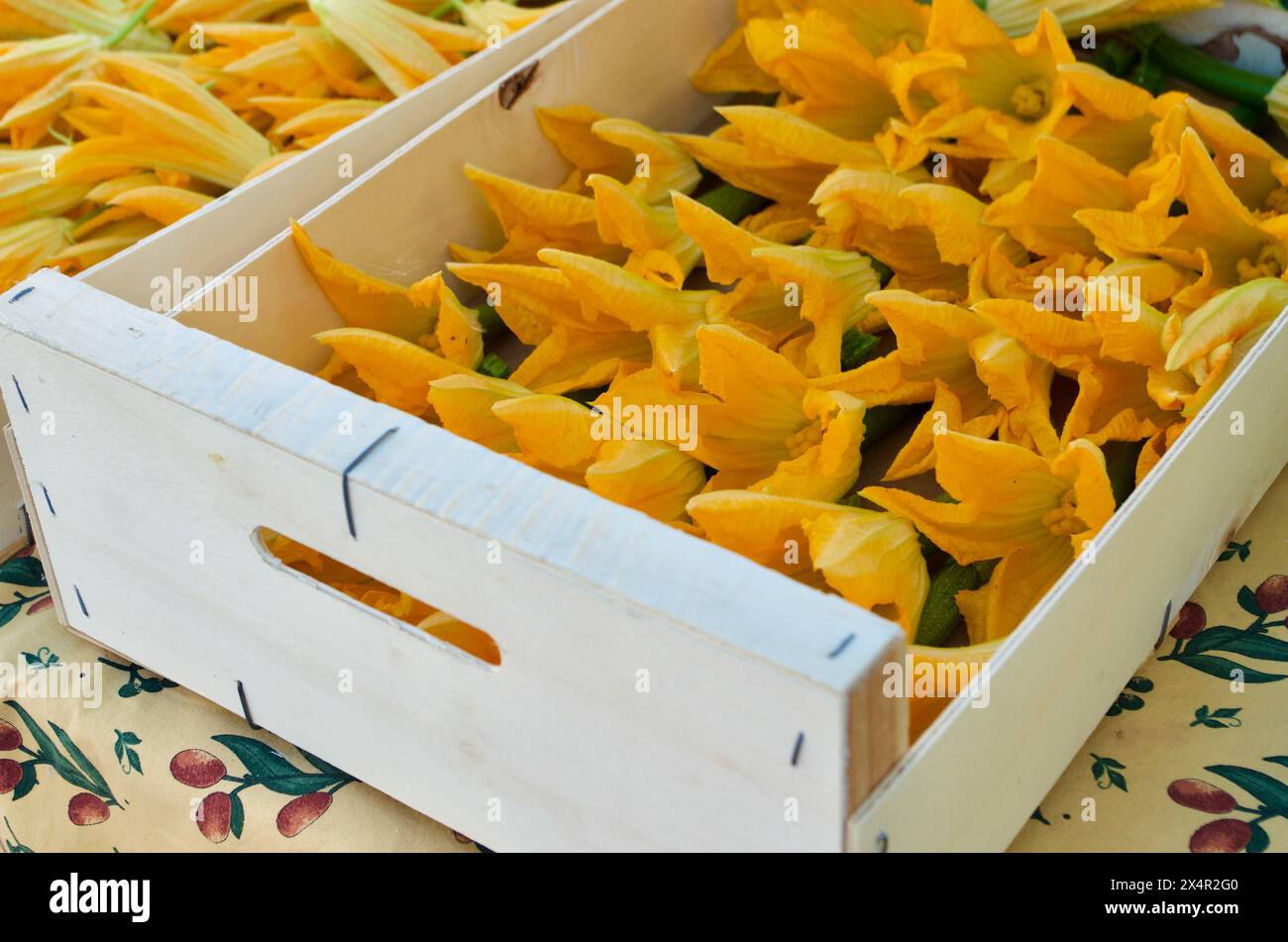 A market stall with fresh newly picked yellow zucchini flowers in ...