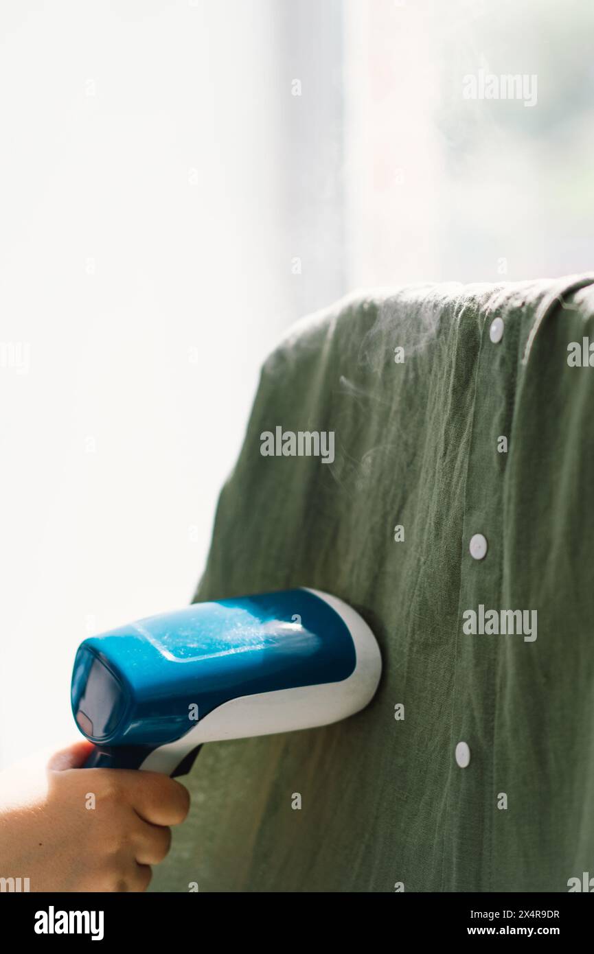 Woman Using Handheld Steamer on a Green Garment at Home During Daytime ...