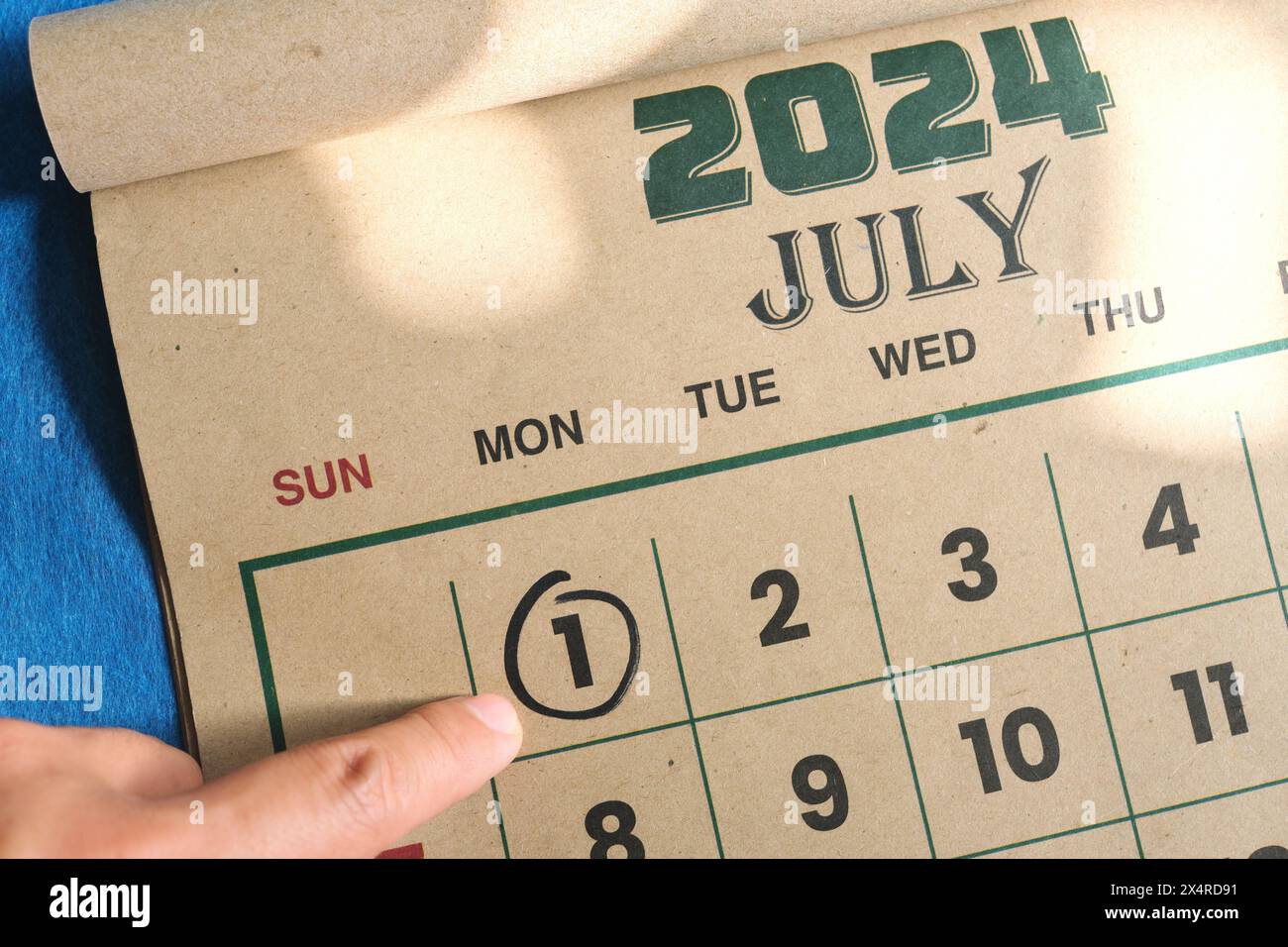 Hand pointing on July 1 2024 date on calendar flat lay in blue ...