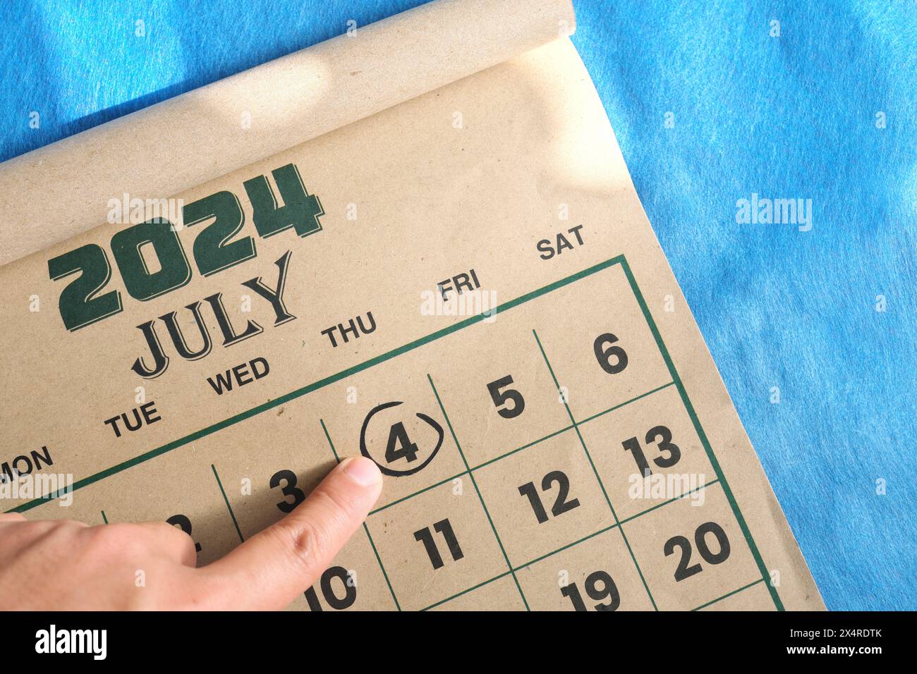Hand pointing on July 4 2024 date on calendar flat lay in blue ...