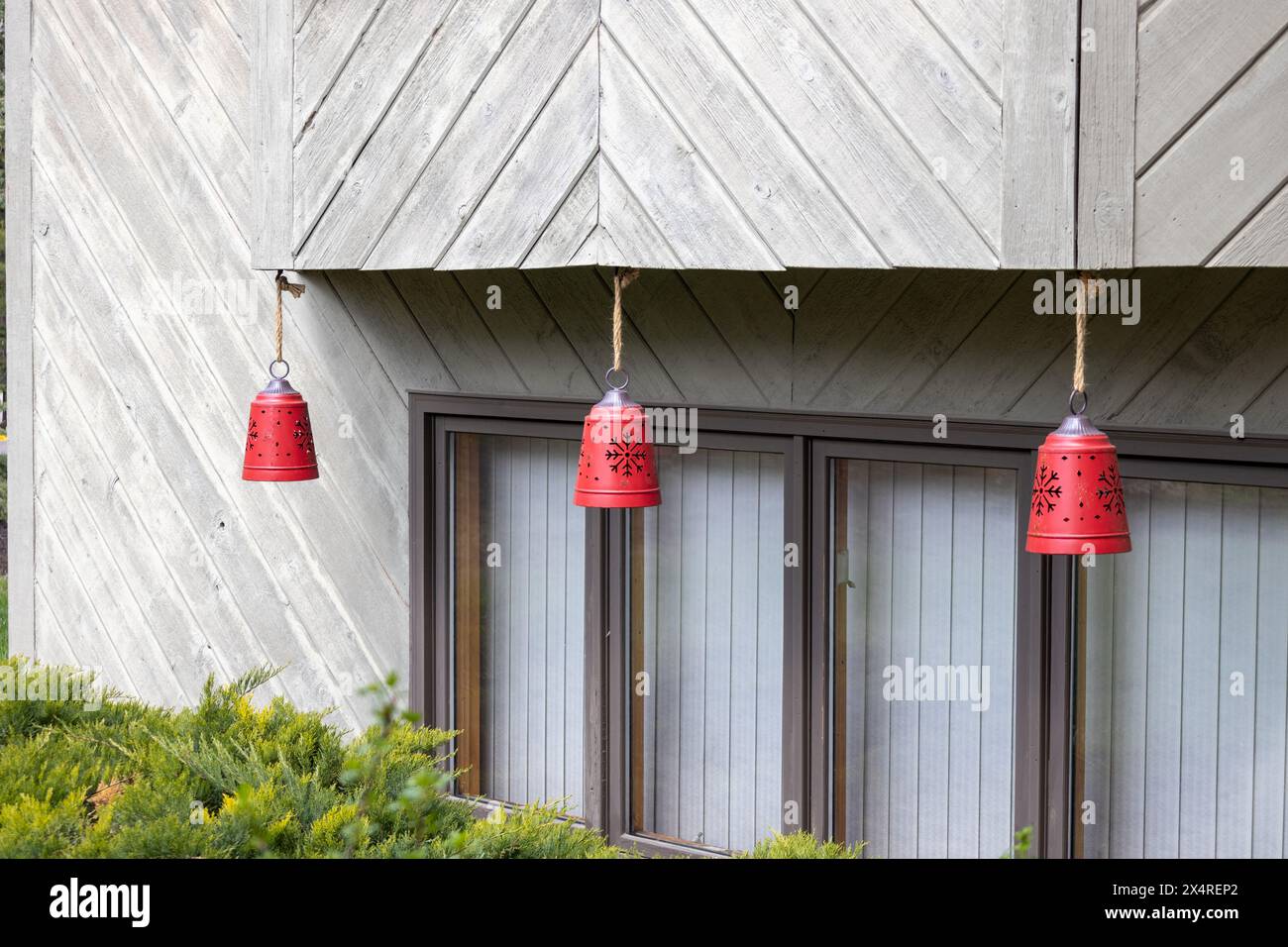 View of three rustic metal holiday bells decorating a large house ...