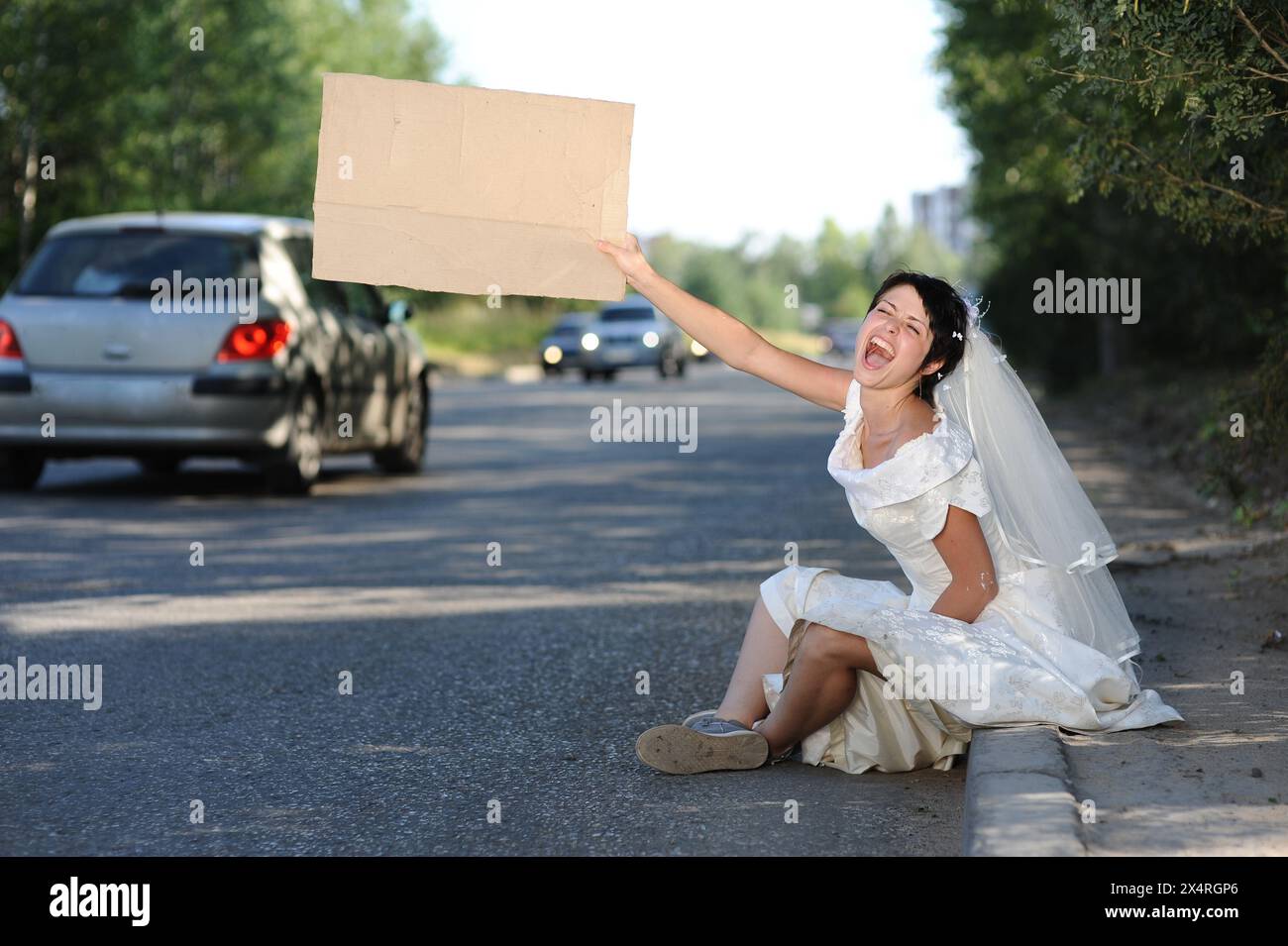 Portrait of a beautiful screaming bride with a blank billboard, sitting ...