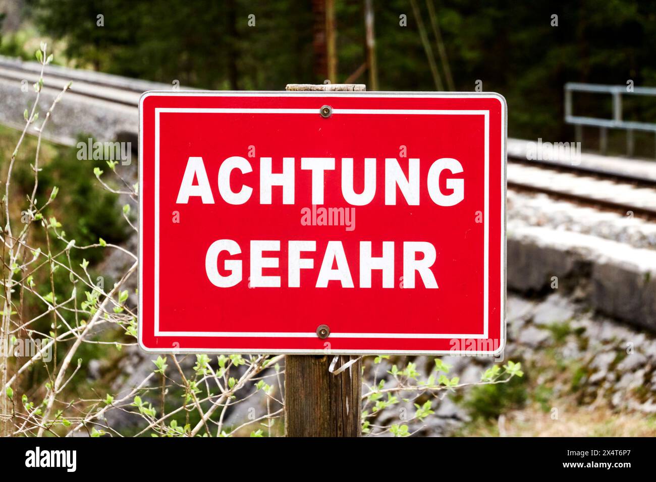 Red and white ‘achtung gefahr’ warning sign beside a railway line ...