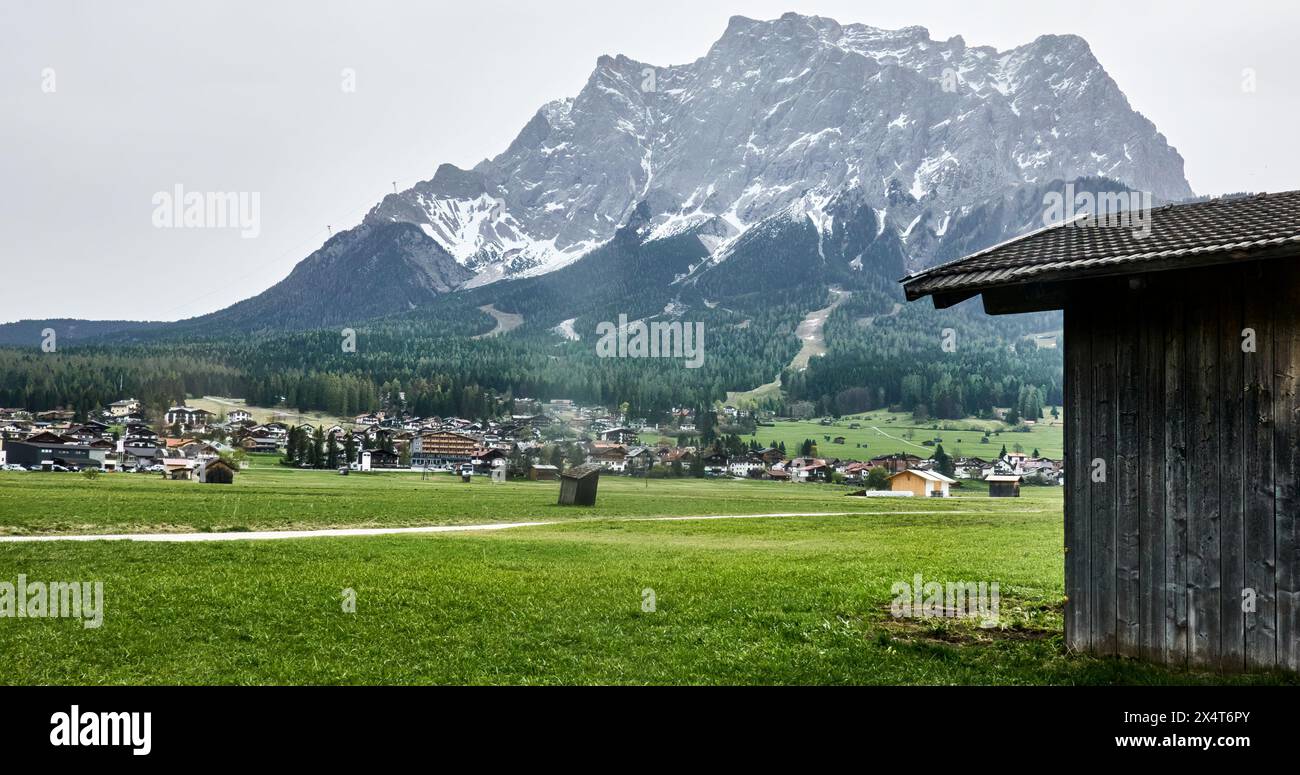 Picturesque view of a small alpine village at the foot of a towering ...
