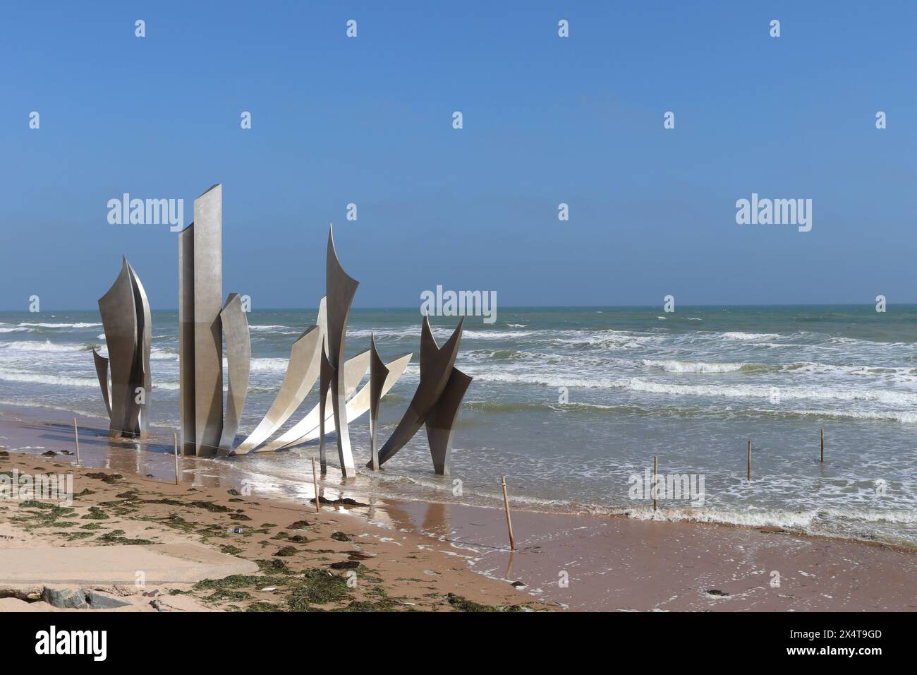 View of monument on Omaha beach. Waves rolling in from the ocean. Blue ...