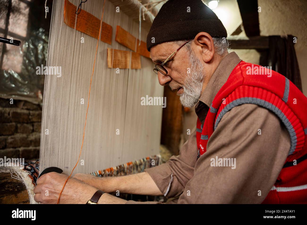 A Kashmiri artisan is seen weaving a traditional carpet in a carpet ...