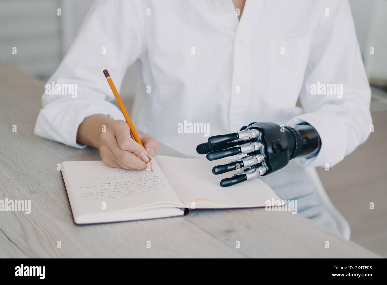 Thoughtful woman with a bionic arm pens ideas in a notebook, blending ...