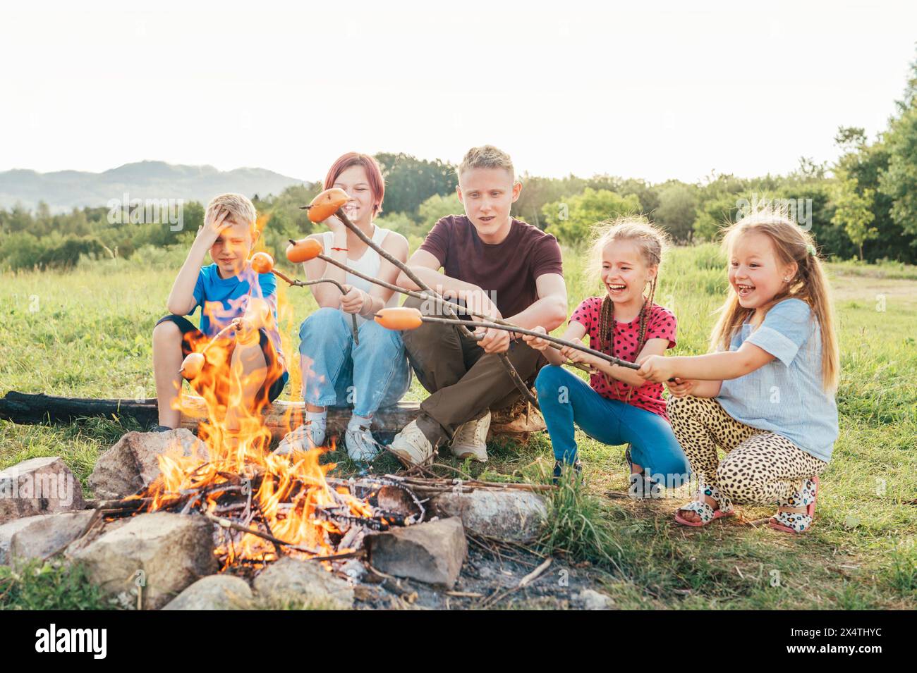Five kids group Boys and girls cheerfully laughed and roasted sausages ...