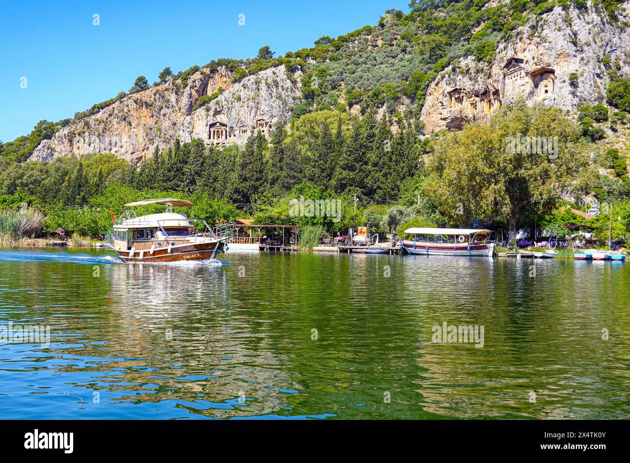 Tourist river boats and Royal Lycian tombs carved into rock face, at ...
