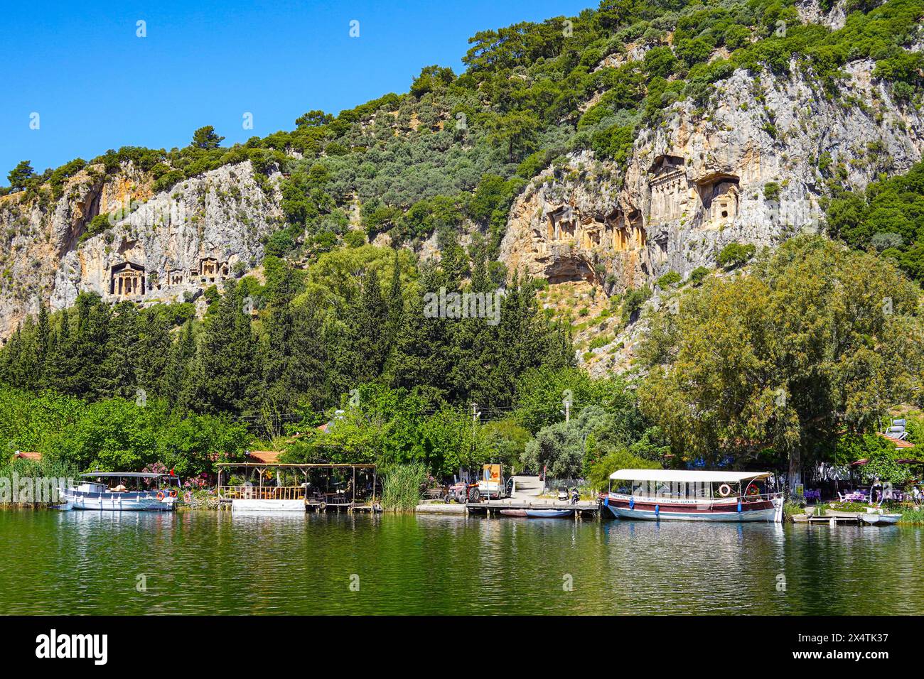 Tourist river boats and Royal Lycian tombs carved into rock face, at ...