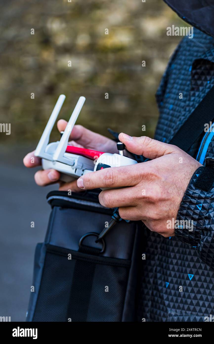 Man piloting a drone using a controller equipped with a joystick and a ...