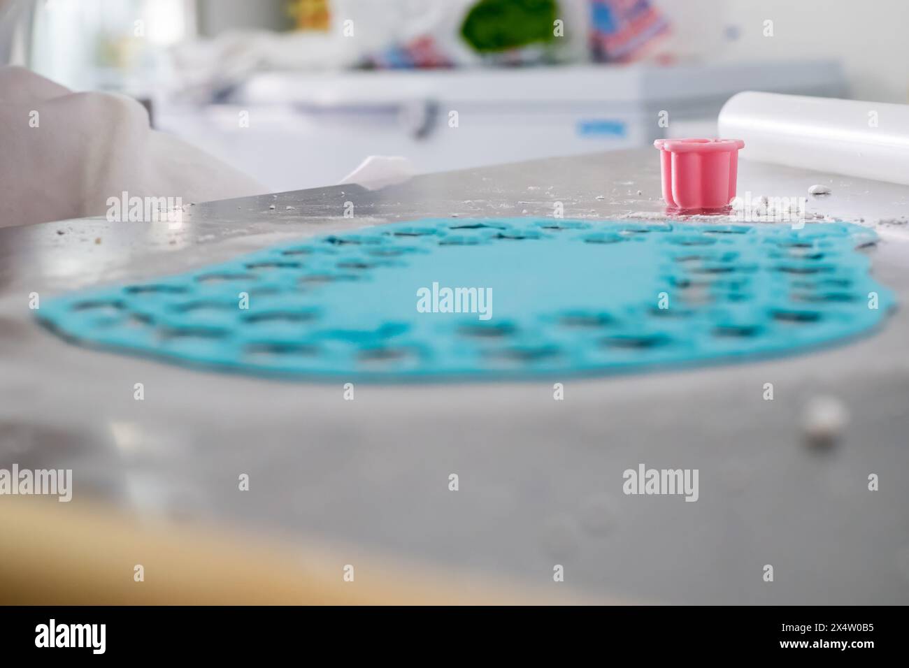 A blue and pink cake pan sits on a counter with a pink icing tip cake ...