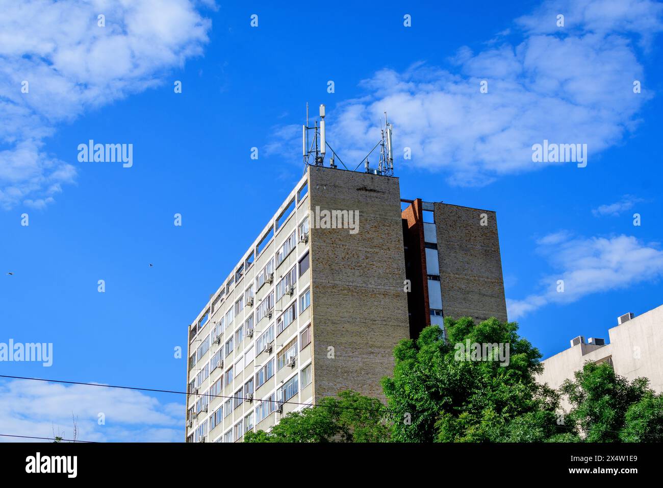 Telecommunications antennas on an old block of flats with clear blue ...