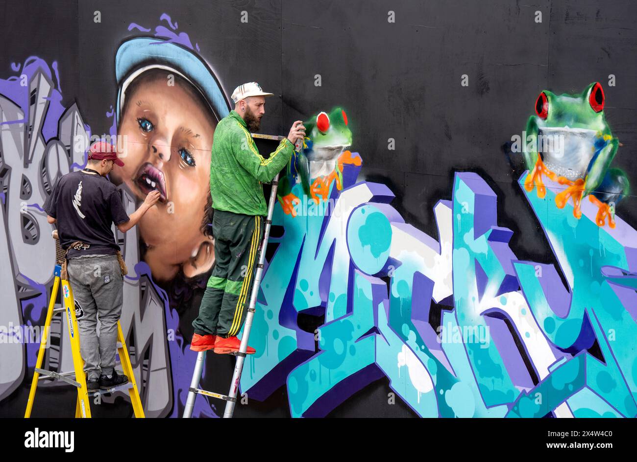 Artists Abism (left) and Micky (right) works on their murals at the ...