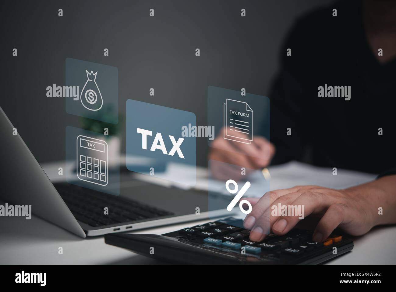 A person works on tax calculations using a laptop, with digital tax ...