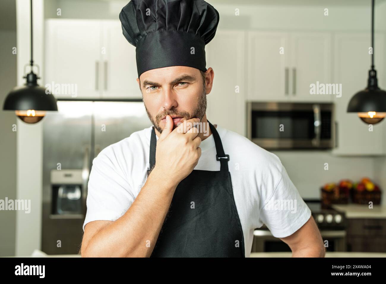 Portrait of chef man in a chef cap in the kitchen. Man wearing apron ...