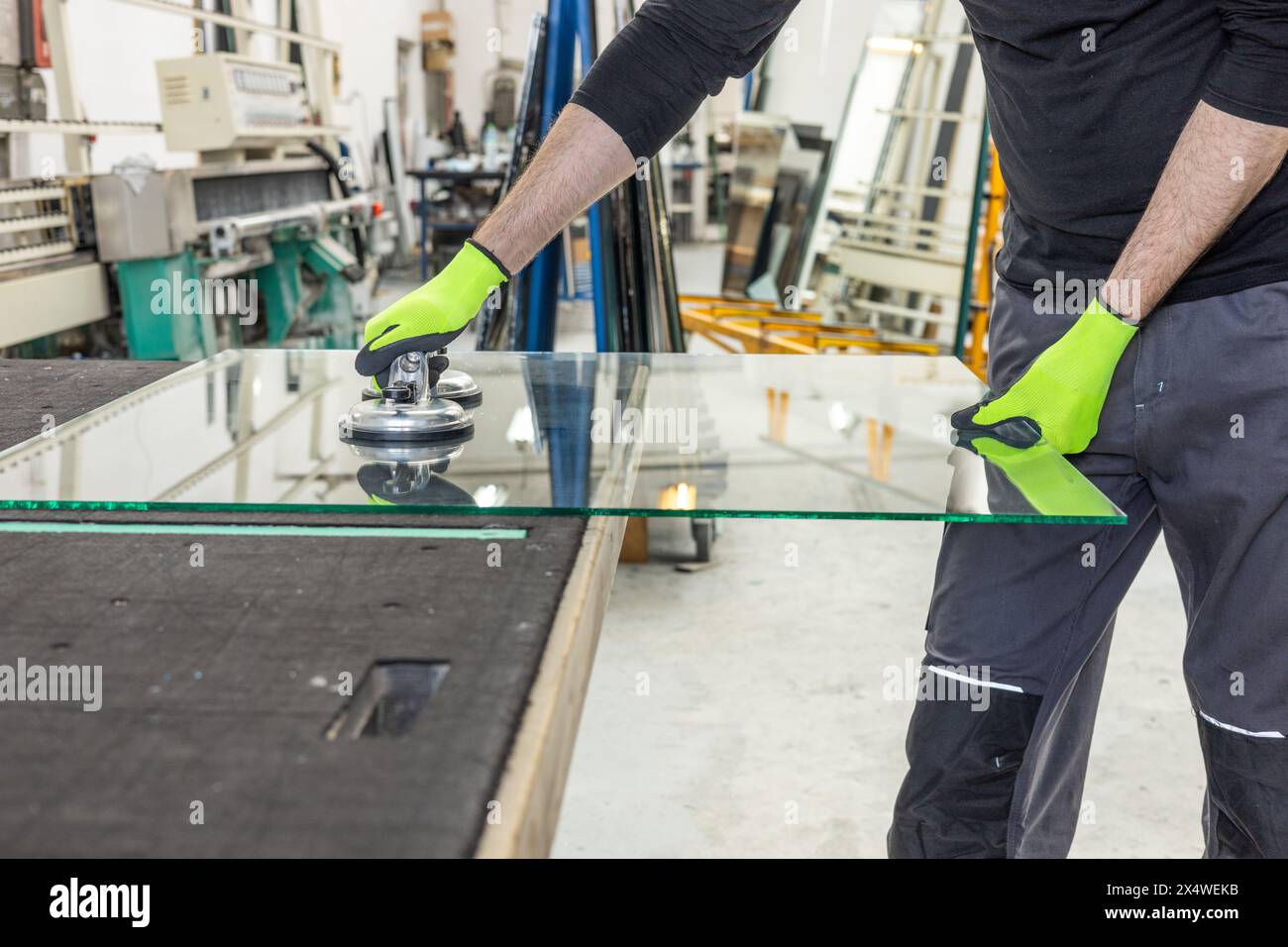 A glazier lifts the glass in the factory using a special glass suction ...