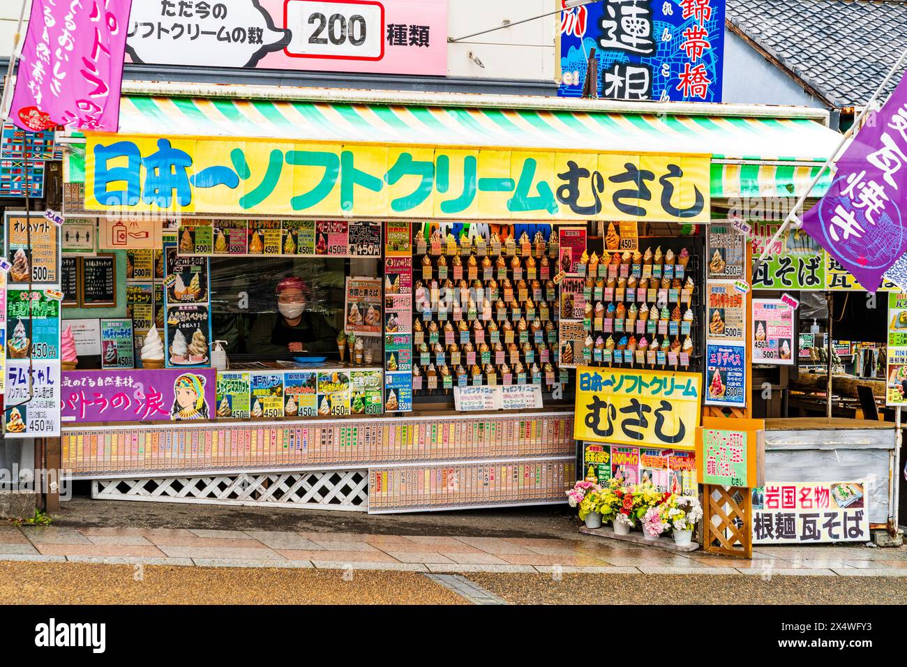 Ice cream shop in the rain at Iwakuni, Japan. Displays outside many plastic cones of different ...
