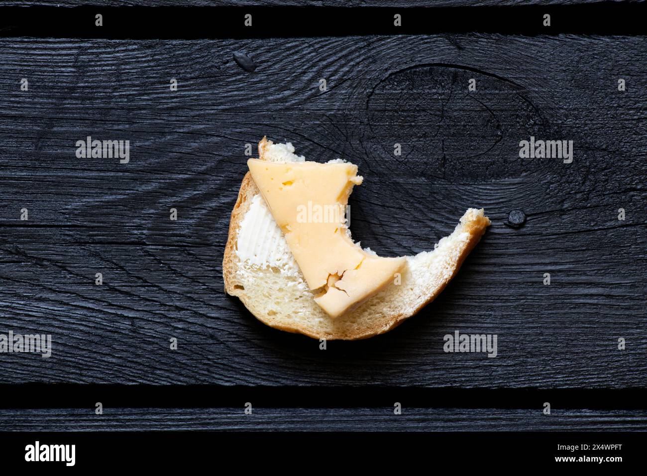 Bitten bread with cheese lies on a black wooden board, eating a ...