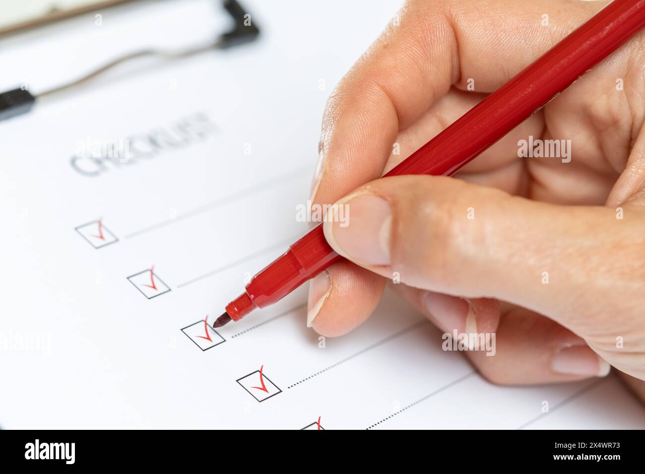 Close-up of a hand using a red marker to check items off a checklist ...