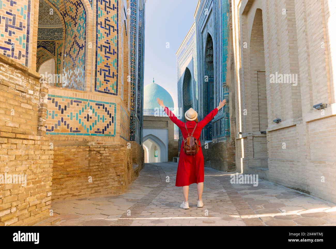tourist woman in red dress clothes stands in the Shah-i-Zinda Ensemble ...