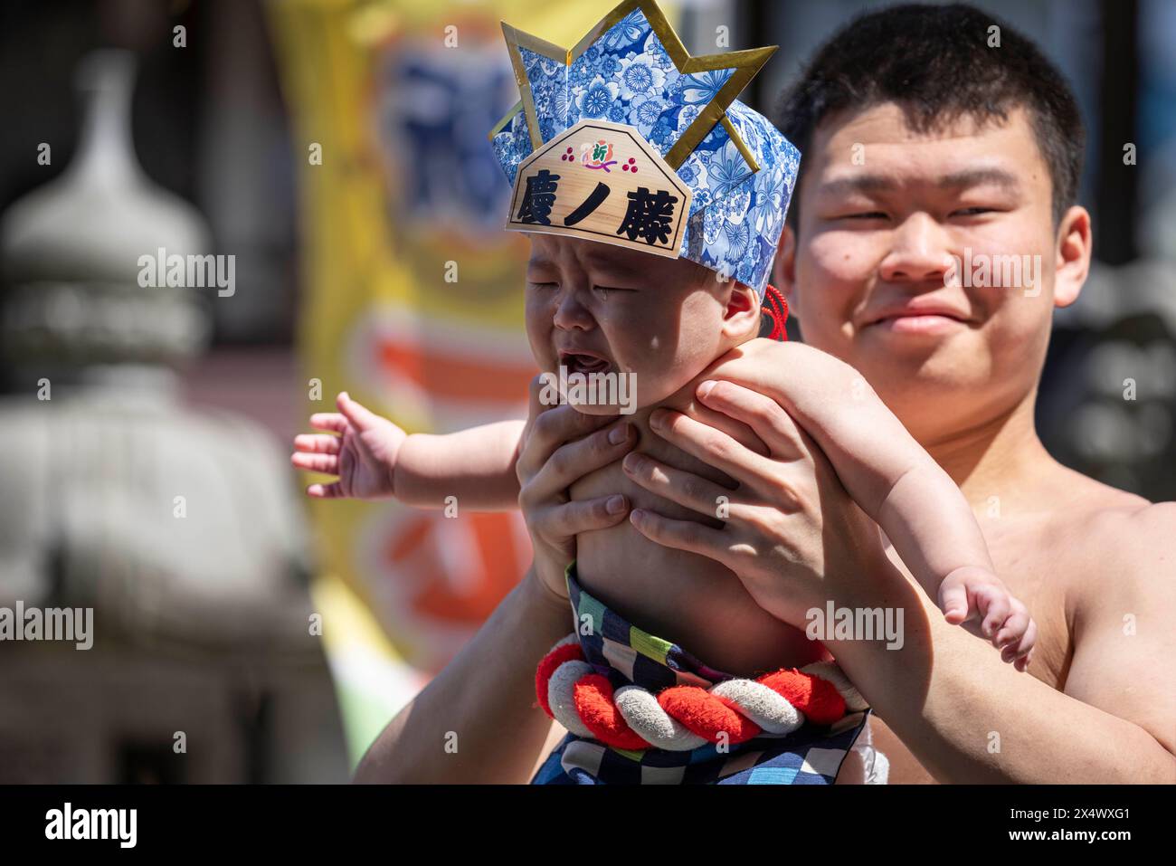 Baby cries in the arms of a sumo wrestler during Nakizumo inside a ...