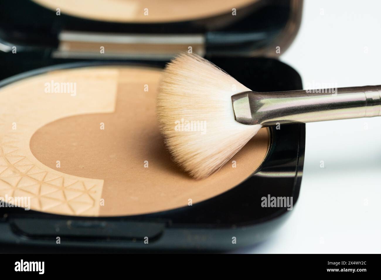 A small makeup kit with bronzing powders and a brush to apply them on ...