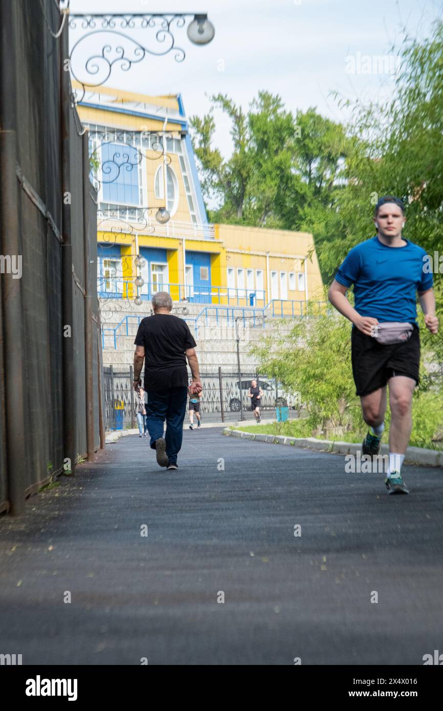 A young guy in an athletic uniform runs straight ahead. Older man ...