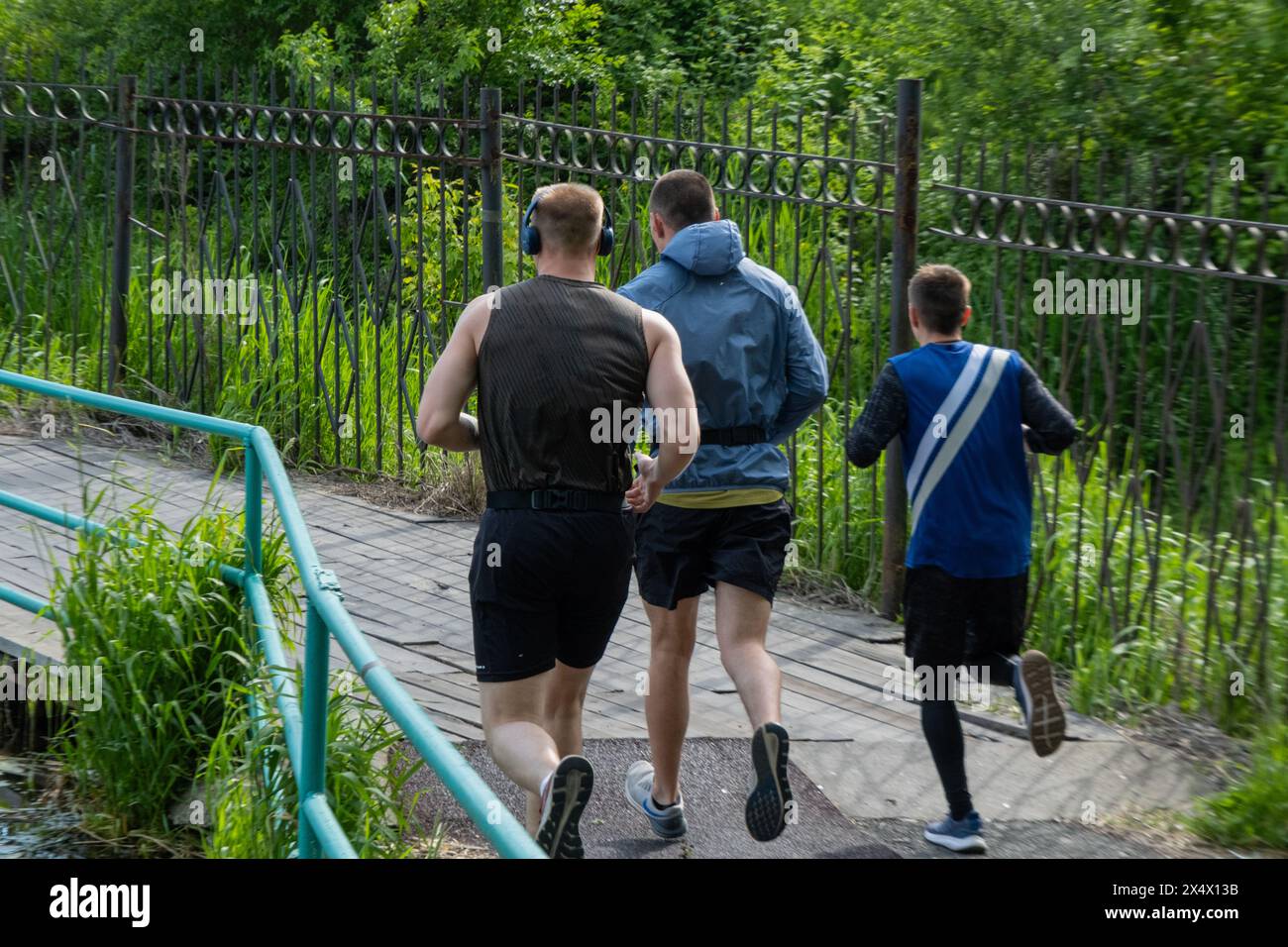 Three people running across the bridge in sportswear. An athlete ...