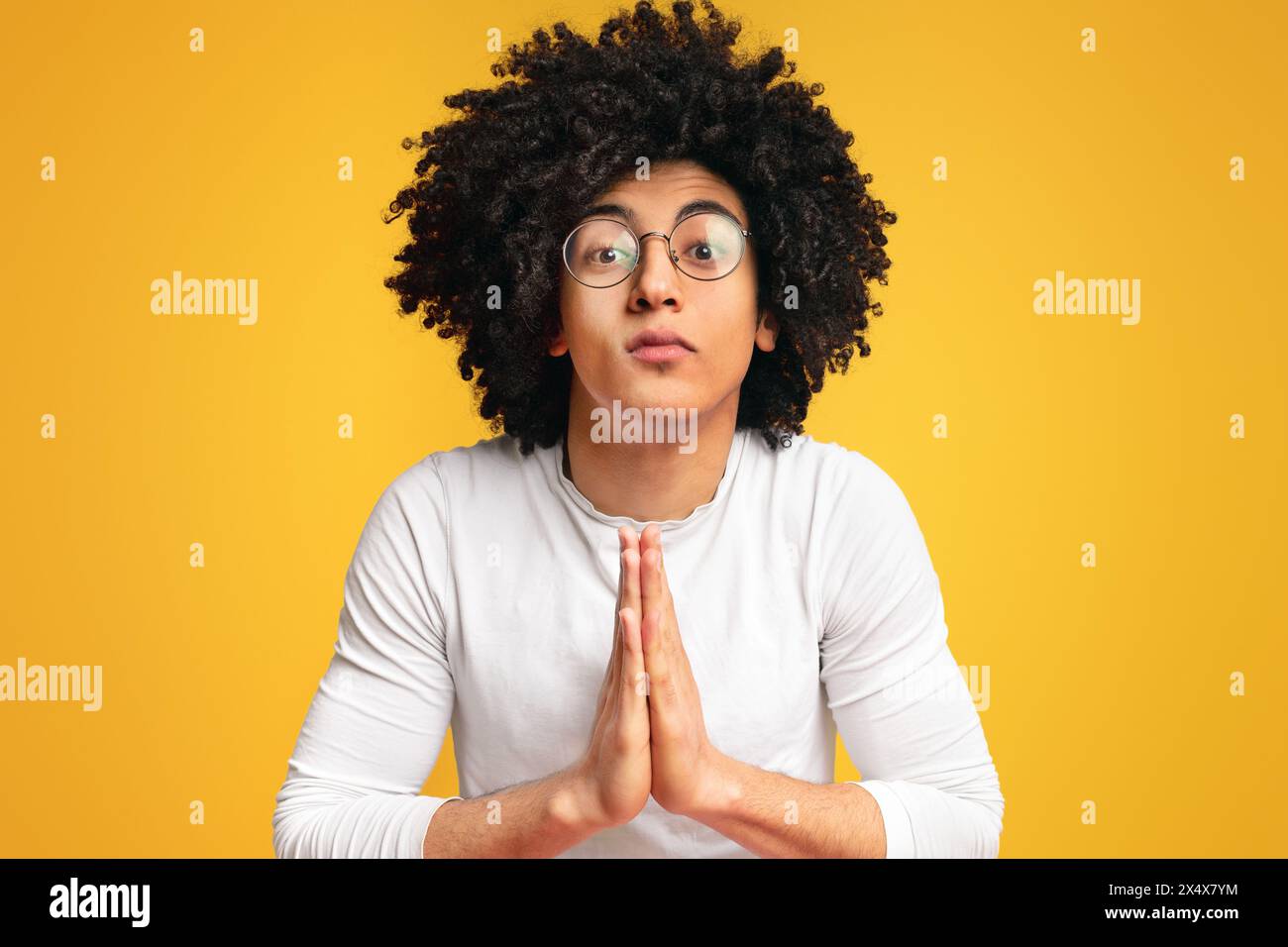 Young black man showing clasped hands in pleading gesture Stock Photo ...