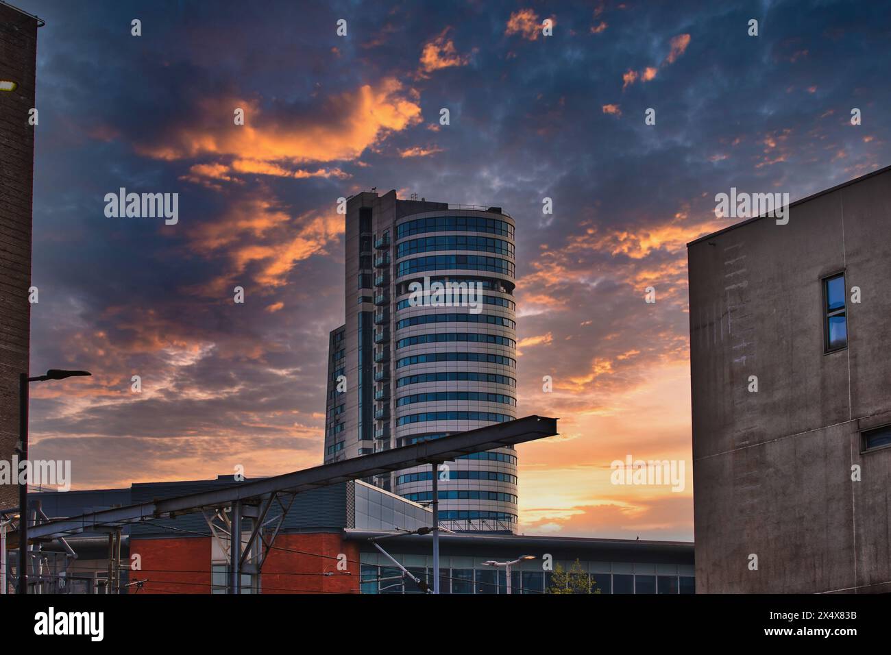 A dramatic sunset over a modern cityscape with a tall glass building ...