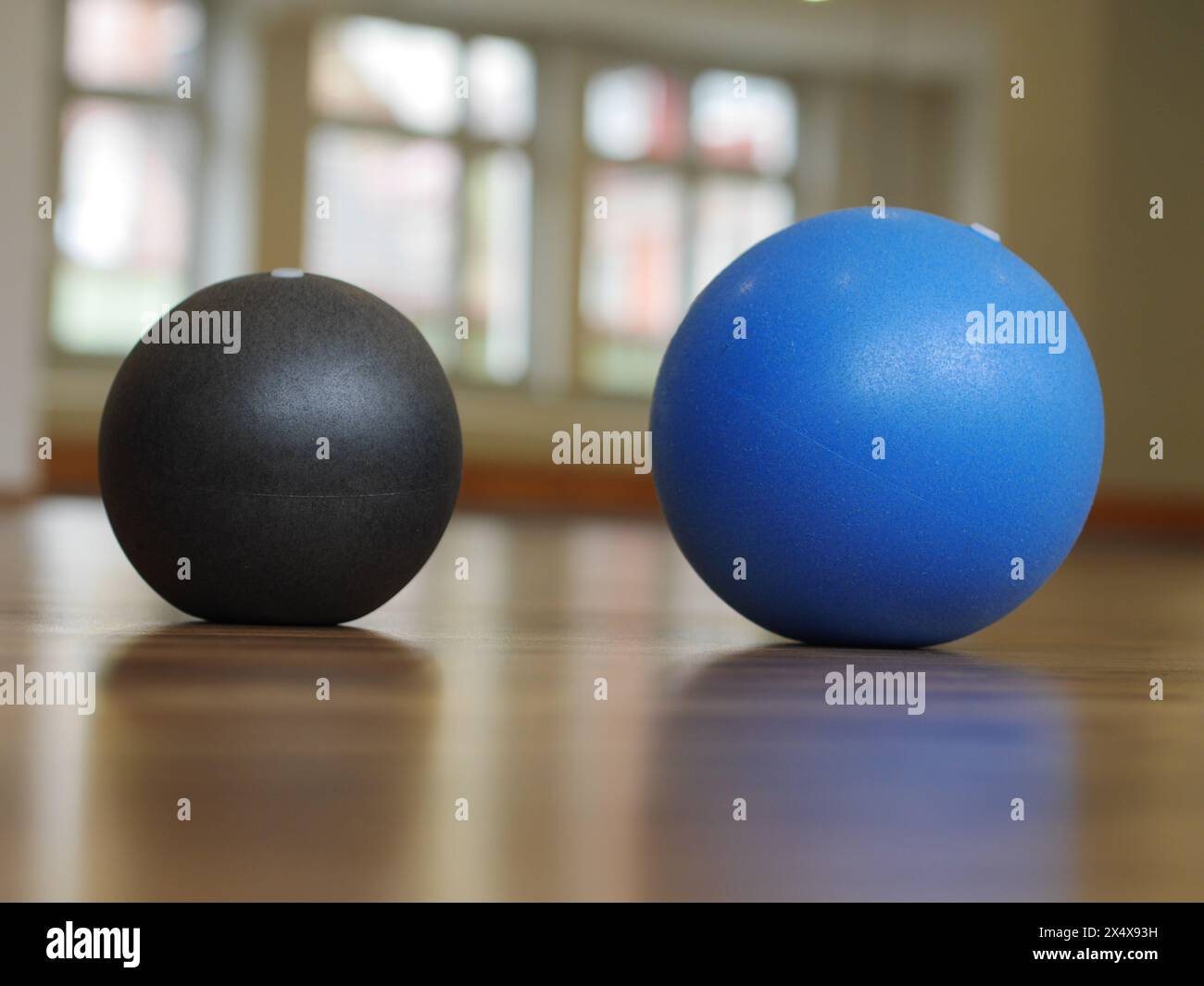 Two balls, one black and one blue, are sitting on a wooden floor Stock ...