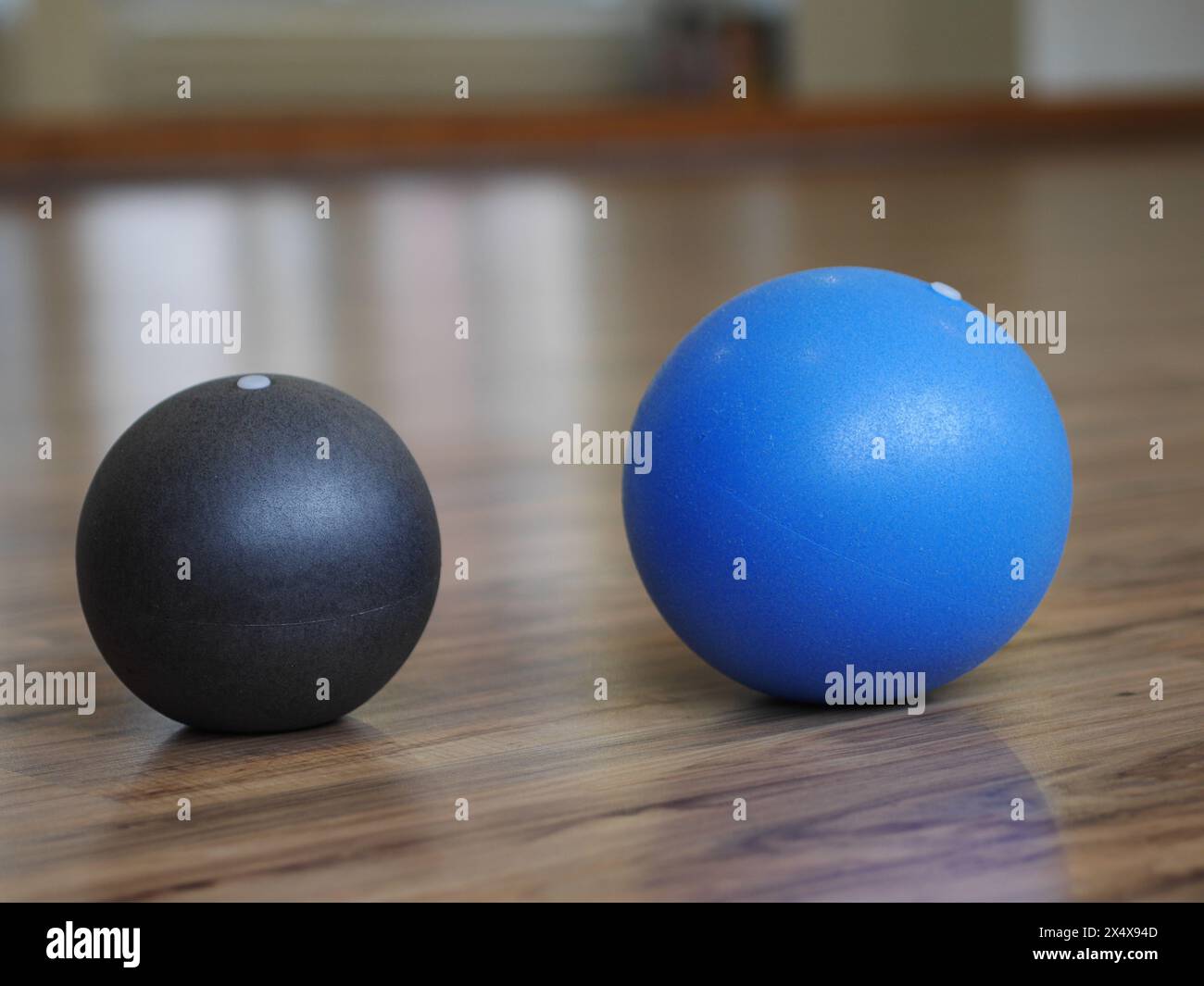 Two balls, one blue and one black, are sitting on a wooden floor Stock ...