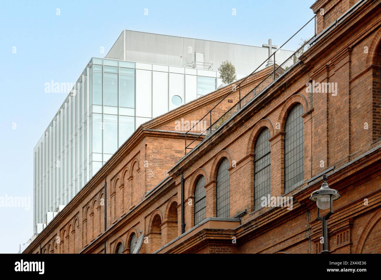 An historic red brick church contrasts with a modern high rise building ...